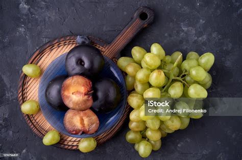 잘 익은 유기농 검은 자두 반으로 잘라 육즙 펄프와 어두운 돌 배경에 흰색 포도의 무리 옆에 도마에 비건 메뉴 건강한 식사 자두에 대한 스톡 사진 및 기타 이미지 Istock