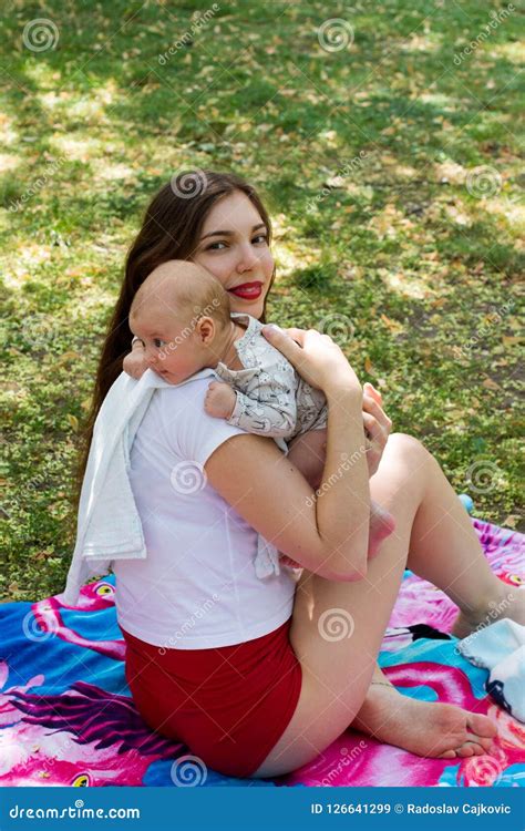 La Giovane Madre Graziosa Negli Shorts Rossi Sta Tenendo Il Suo Bambino