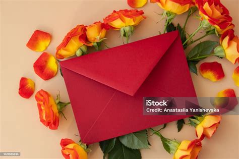 중립 베이지 색 배경에 우편 빨간 봉투에 아름다운 빨간 장미 꽃 텍스트를위한 복사 공간 봄 시간 휴가를위한 인사말 카드 꽃 배달