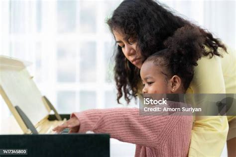 아프리카 계 미국인 어린 소녀가 집에서 여성 선생님과 피아노를 연주합니다 어린 소녀 아이 학생에게 보육원에서 피아노 연주를