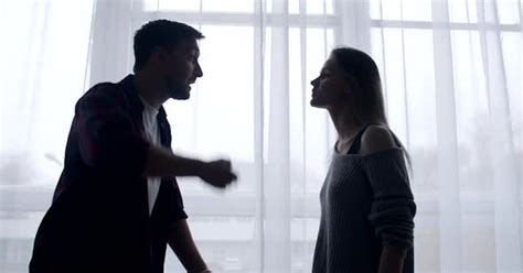 Married Couple Swears In Living Room Background Of Curtains And Windows Husband Insults Wife