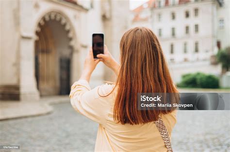 여름날 야외에서 핸드폰으로 사진을 찍는 젊은 여자 사진을 찍고 있는 여성 관광객의 뒷모습 Brand Name Smart Phone에 대한 스톡 사진 및 기타 이미지