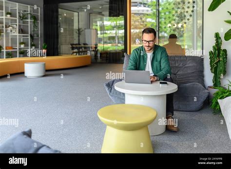 Male Computer Programmer With Glasses Working Over Laptop While Sitting