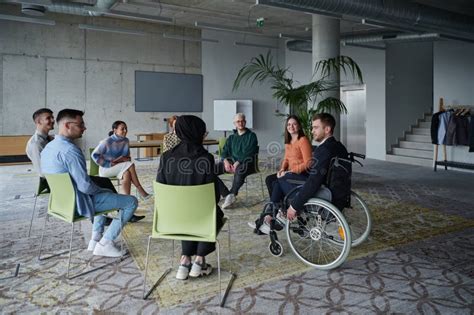 In A Modern Office A Diverse Group Of Business Individuals Is Seen Gathered In A Circle