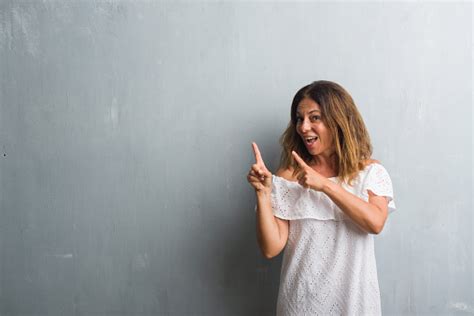 중세 스페인 여자 회색 그런 지 벽 웃 고 옆에 두 손과 손가락으로 가리키는 카메라를 보고 서 가리키기에 대한 스톡 사진 및