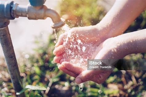 자연 녹색 공원에서 여자 손에 탭에서 물 과 일몰 하늘 보케 태양 빛 추상적 인 배경 환경 및 건강 관리 개념 빈티지 톤 필터 효과 색상 스타일입니다 개념에 대한 스톡 사진