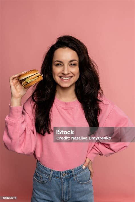 스튜디오 사진 촬영 중에 그녀가 가장 좋아하는 영양가 있는 샌드위치를 보여주는 빛나는 미소를 가진 젊고 예쁜 갈색 머리 패스트 푸드 소비 개념 25 29세에 대한 스톡 사진