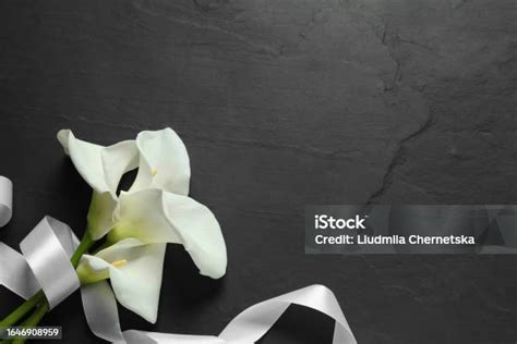 아름다운 칼라 백합 꽃과 검은 테이블에 하얀 리본이 놓여 있고 텍스트를 위한 공간이 평평하게 놓여 있다 장례식 상징 부고에 대한