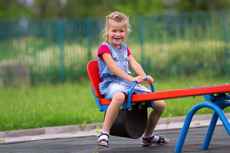 작은 귀여운 젊은 금발의 아이 소녀는 밝은 녹색 흐린 배경에 따뜻한 화창한 날에 그네를 보았다에 앉아있다 어린 시절의 기쁨과 슬픔 야외 활동 개념 건강관리와 의술에 대한