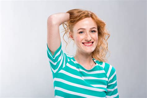 회색 배경에 스튜디오에서 파란색의 스트립과 여름 드레스에 빨간 곱슬 머리와 젊은 아름 다운 여자의 클로즈업 초상화 여름 방학