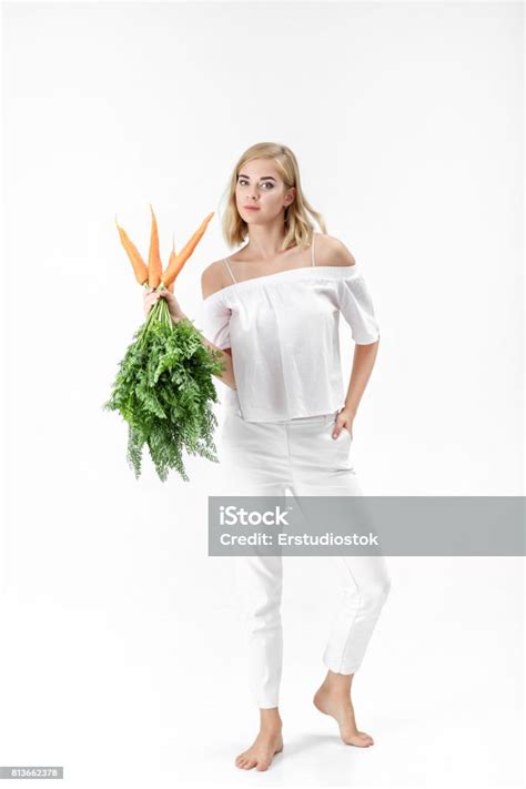 아름 다운 금발의 여 자가 녹색 신선한 당근 들고 흰색 바탕에 나뭇잎 건강 및 다이어트 건강한 생활방식에 대한 스톡 사진 및 기타 이미지 건강한 생활방식 건강한 식생활