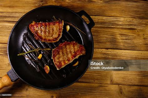 나무 테이블에 주철 그릴 프라이팬에 로즈마리 마늘 향신료를 곁들인 돼지고기 스테이크구이 위쪽 보기 0명에 대한 스톡 사진 및 기타 이미지 Istock