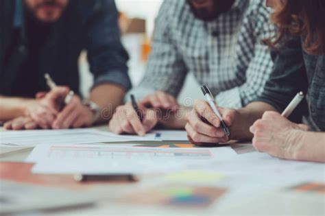Business Team Analyzing Financial Charts And Graphs At A Desk With Laptops And Calculators Stock
