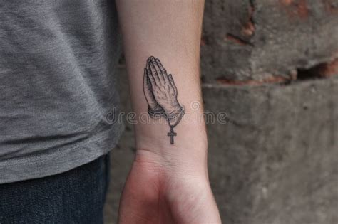 Close Up Of A Praying Hands Tattoo With A Rosary And Cross Symbolizing