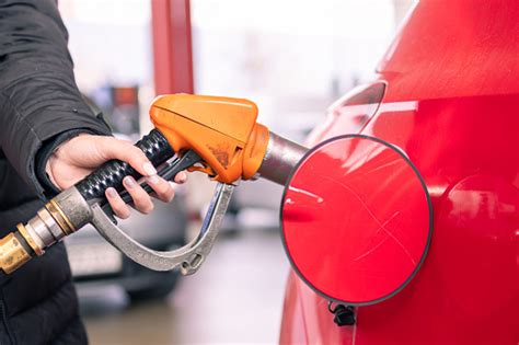 액화 석유 가스로 작동하는 빨간 Lpg 자동차의 연료 탱크를 다시 채우기 위해 가스 호스를 들고 있는 알아볼 수 없는 여자의 손의 측면 보기 클로즈업 가솔린에 대한 스톡