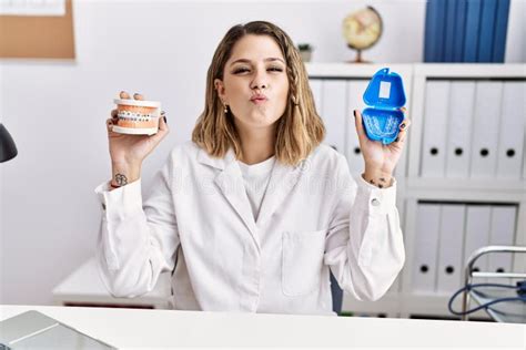 Young Hispanic Woman Working At Dentist Clinic Holding Brackets And