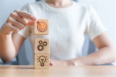 기어와 전구 아이콘 블록 위에 다트 보드를 들고있는 여자 손 사업 계획 프로세스 목표 전략 목표 임무 행동 목표 팀워크 및 아이디어 개념 포부에 대한 스톡 사진 및 기타