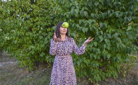 Outdoor Portrait Of Beautiful Brunette Girl Throwing A Green Apple Into