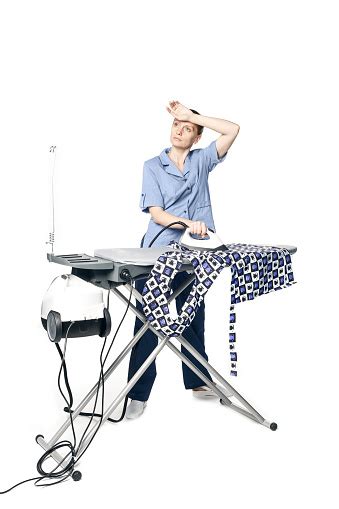 하녀의 유니폼을 입은 아름다운 젊은 여성이 피곤하게 이마에서 땀을 닦고 흰색 배경에 고립 된 옷을 쓰다듬습니다 가사 집안일에 대한 스톡 사진 및 기타 이미지 Istock