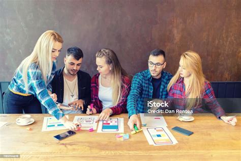 직장에서 창조적 인 젊은 웹 디자이너팀과 웹 사이트 개발 프로젝트 현대 Ui 디자인 레이아웃 스케치 도면과 웹 아이디어와 전략을 공유하는 사람들과 테이블에 응답 와이어