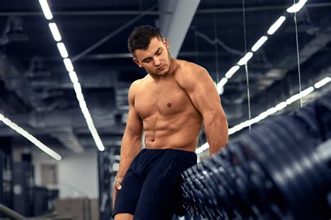 덤 벨 랙 근처 체육관에서 근육 질의 보디입니다 강한 운동 남자 몸 복 부 근육 가슴 근육 팔 뚝 삼각 근을 보여줍니다 운동 해 무게를 얻고 있다 보디 빌딩 개념입니다 6개