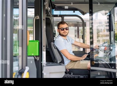 Portrait Of City Shuttle Bus Driver Man Wearing Sunglasses Sitting In Drivers Cabin While