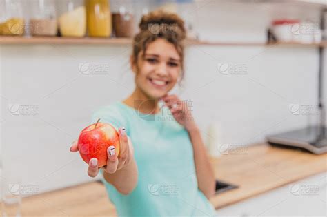快乐的年轻女人在厨房吃苹果。饮食。节食的概念。健康食品。