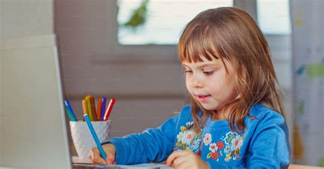 아이 방의 테이블에 앉아 원격 학습을 위해 노트북을 사용하여 숙제를 하는 행복한 네 살 소녀 원격 온라인 학습 개념입니다 사진 Unsplash의 유치원 이미지