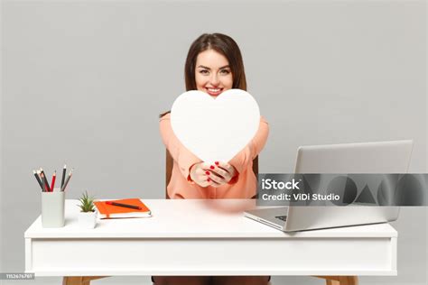 복사 공간 앉아 흰색 마음을 들고 파스텔 캐주얼에 젊은 웃는 여자 회색 배경에 고립 된 Pc 노트북 책상에서 작업 성취 비즈니스
