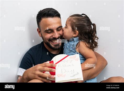 Happy And Smiling Adult Man Receiving A Kiss From His Daughter And A