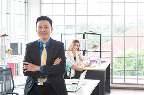 성숙한 사업가는 그의 현대 사무실에서 테이블 옆에 서 사무실에 서있는 자신감 있는 중년 사업가 잘생긴 Ceo는 책상에서 일하는 배경에 동료들과 함께 사무실에 서서 미소를