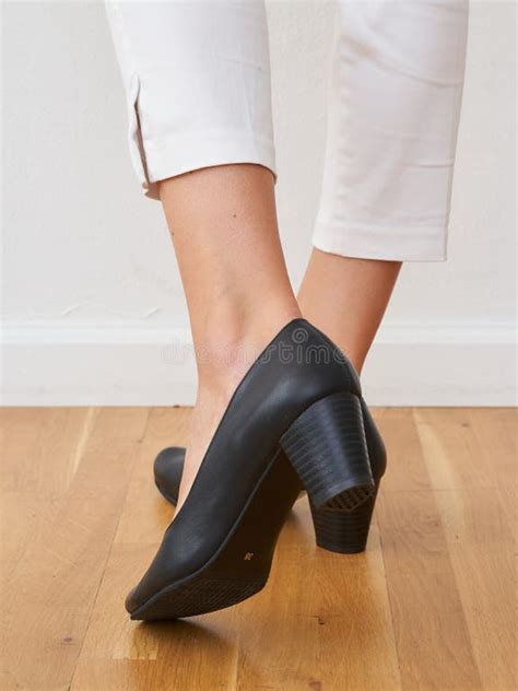 Slim Woman In Stylish Black Heels Poses On Wooden Floor In Bright
