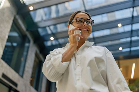 쾌활한 여성 기업가는 현대적인 사무실 배경에 서서 고객과 전화 통화를 하고 있다 45 49세에 대한 스톡 사진 및 기타 이미지 45 49세 Brand Name