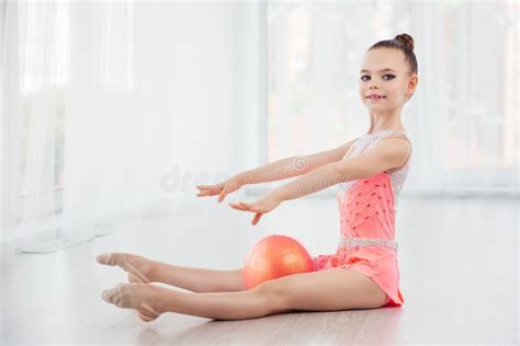 Красивая маленькая девушка гимнаста в розовом платье Sportswear элементе гимнастики