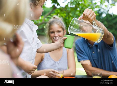 Family together outdoors, father pouring glass of juice for son Stock ...