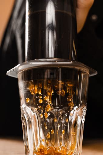 컵 클로즈업에서 떨어지는 커피 방울 에어로 프레스 커피 컵에 커피를 붓는 과정 바리스타는 커피 방울을 따르기 위해 에어로프레스를