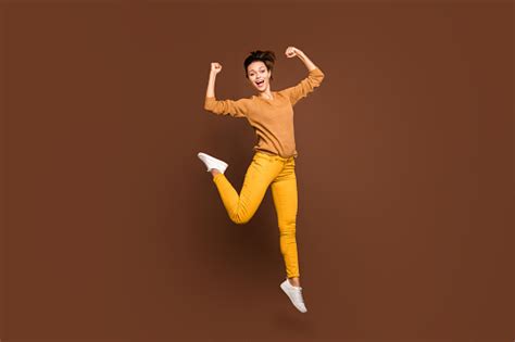 전체 길이 바디 크기 사진 의 쾌활한 긍정적 인 흥분 좋은 달콤한 강력한 트렌디 한 여자 친구는 흥분 얼굴 표정 고립 된 갈색 파스텔 색상 배경으로 점프하는 동안 당신에게