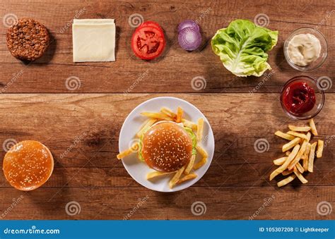 Hamburger Ingredients On Wooden Table With An Assembled Burger I Stock