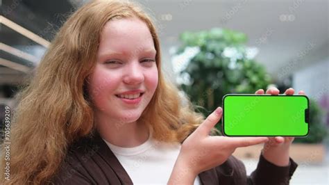Happy Smiling Ginger Teen Girl Showing Phone With Green Screen Chroma Key And Talking Words At