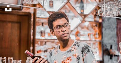 흰색과 파란색 꽃무늬 크루넥 티셔츠를 입은 남자가 검은색 스마트폰을 들고 있다 사진 Unsplash의 무료 소년 이미지