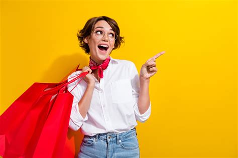 놀란 매력적인 아가씨의 초상화는 쇼핑몰 가방을 잡고 노란색 배경에 고립 된 직접 손가락 빈 공간을 보입니다 25 29세에 대한 스톡 사진 및 기타 이미지 Istock