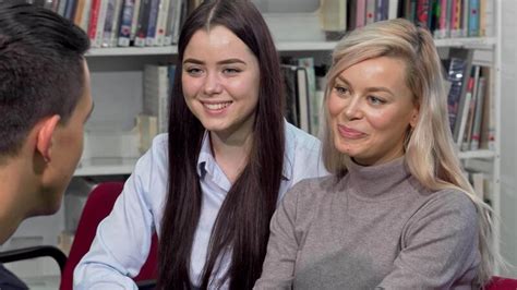 Joyful College Girls Engaging In Lively Conversation With Their Classmate At The Campus Library