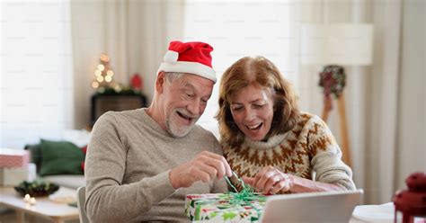 행복한 노부부는 크리스마스에 집에서 실내에서 선물을 열고 가족과 화상 통화를 합니다 사진 Unsplash의 산타 모자 이미지