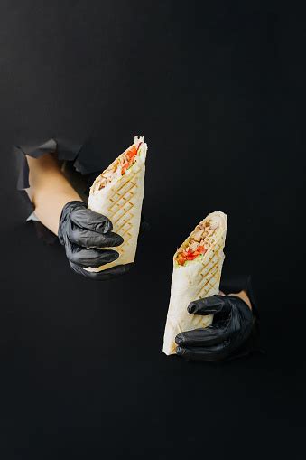 검은 종이 배경의 찢어진 구멍을 통해 기증자 또는 Shawarma를 들고 있는 손 길거리 음식 개념 슈와마에 대한 스톡 사진 및 기타 이미지 Istock