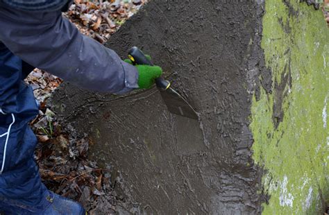 진흙 시멘트 석고와 벽을 던지는에 재생 어린 소년 그들은 아빠에게서 도구를 빌렸습니다 주걱 타일 접착제처럼 진흙을 얼룩 군사 장애물 콘크리트 피라미드 숲에서 가을에 대한