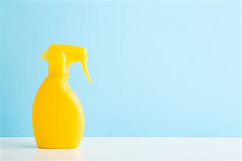 밝은 파란색 벽 배경에 있는 흰색 테이블에 있는 자외선 차단제 또는 청소 세제의 노란색 스프레이 병 파스텔 색상 근접 촬영 텍스트를위한 빈 장소 정면도 0명에 대한 스톡