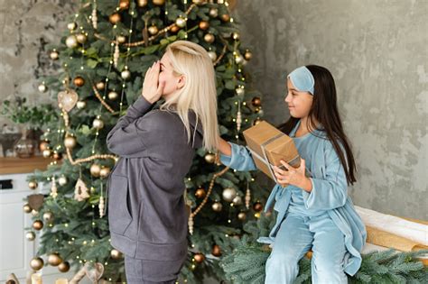 메리 크리스마스와 해피 홀리데이 쾌활한 엄마와 그녀의 귀여운 딸 소녀는 선물을 교환 부모와 어린 아이는 실내 크리스마스 트리 근처 재미를 방에 선물을 가진 사랑하는 가족