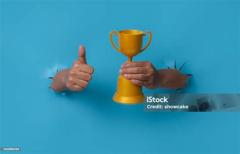 챔피언 황금 트로피를 들고 있는 여성의 손이 파란색 종이 배경을 뚫고 나옵니다 개념에 대한 스톡 사진 및 기타 이미지 개념 개념과 주제 구멍 Istock