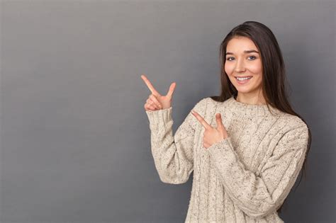 텍스트 또는 제품에 대한 공간을 복사합니다 젊은 여자 에 스웨터 서 스튜디오 고립 에 회색 가리키는 옆으로 미소 행복 갈색 머리에 대한 스톡 사진 및 기타 이미지 Istock