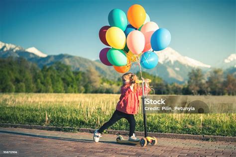 아 이들은 배운다 화창한 여름 날에는 공원에서 스쿠터를 타고 유아 소년과 소녀는 롤러를 타고 안전 헬멧에 아이는 스쿠터와 함께